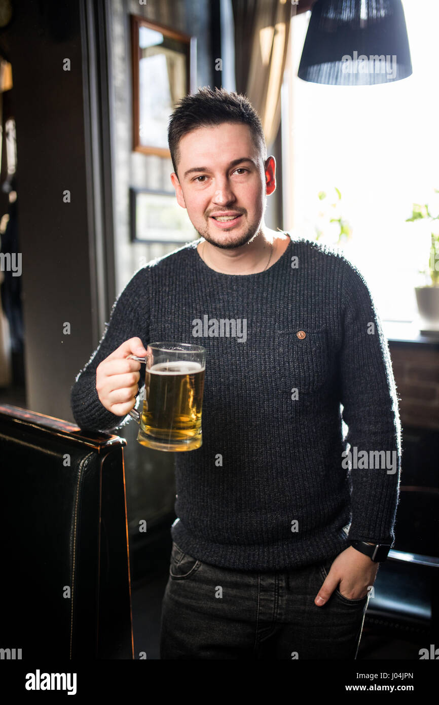 man in a pub or bar holding mug the beer high in the air for cheers in ...