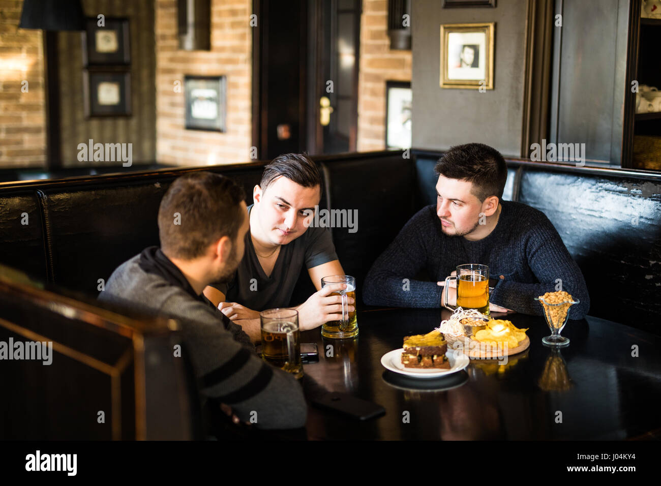 Meeting at the pub. Three happy friends drinking beer at the pub Stock ...