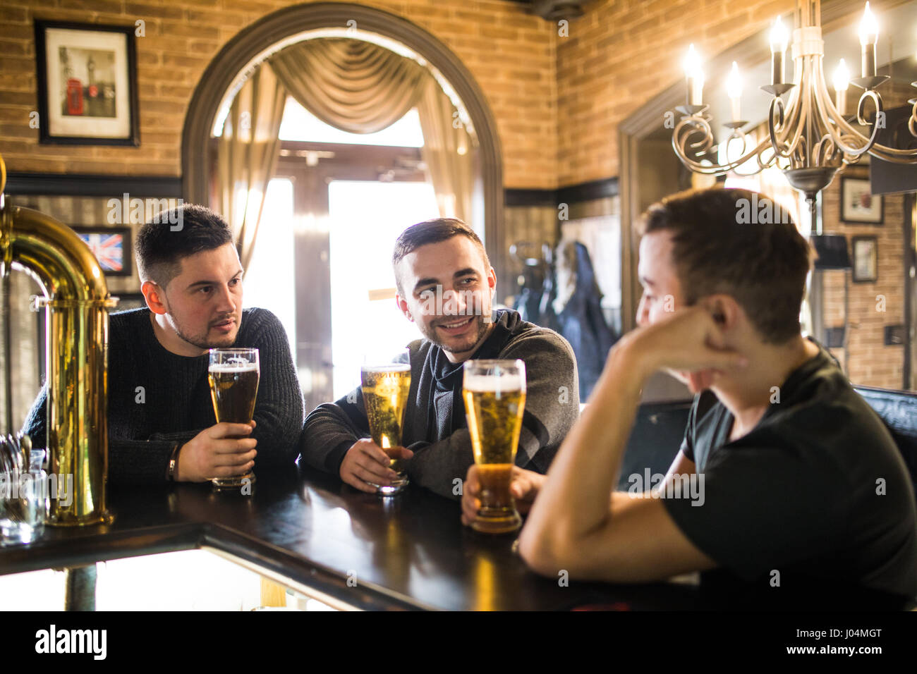 Cheerful old friends having fun and drinking draft beer at bar counter ...