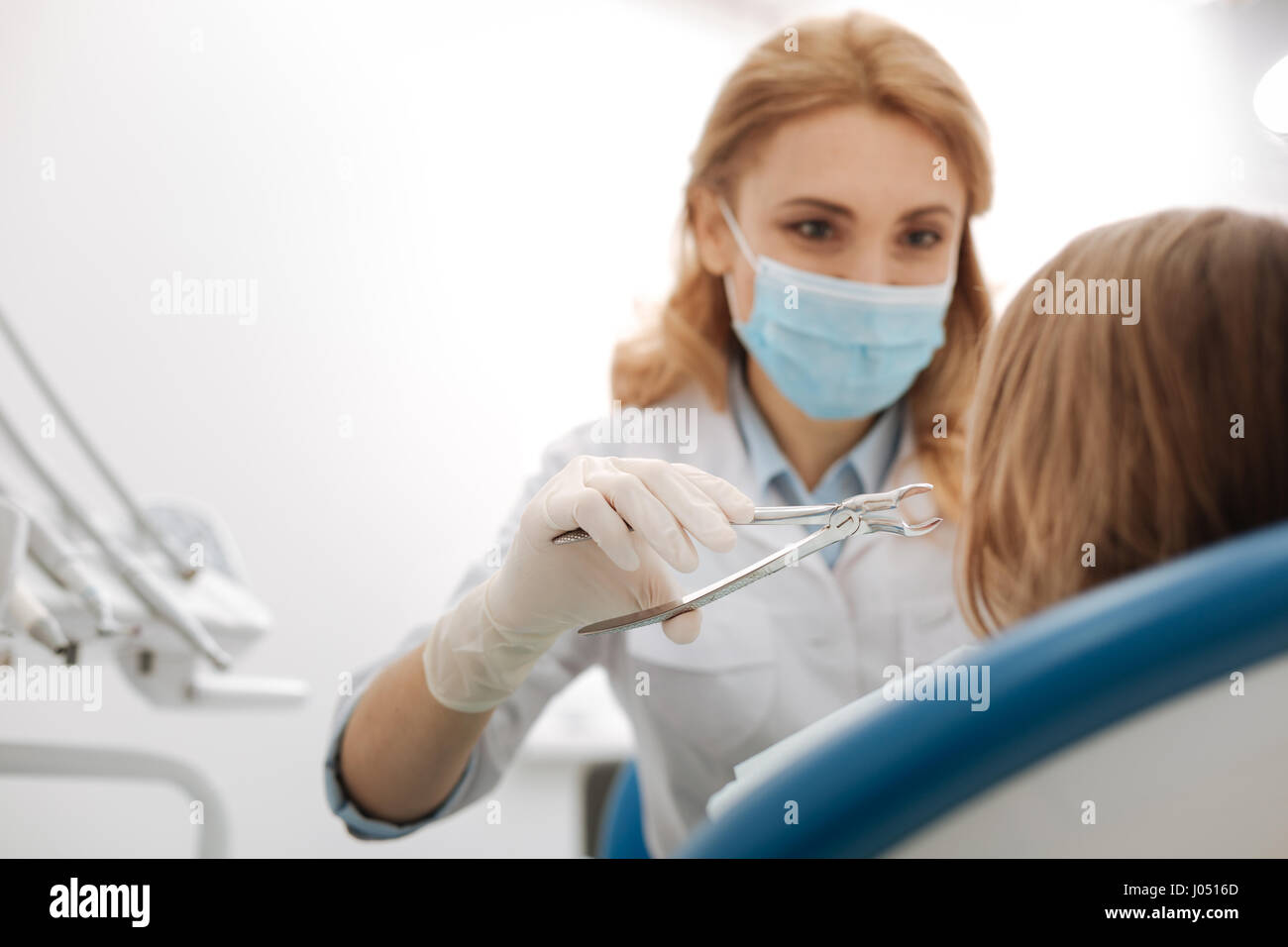 Wonderful experienced dentist removing patients tooth Stock Photo - Alamy