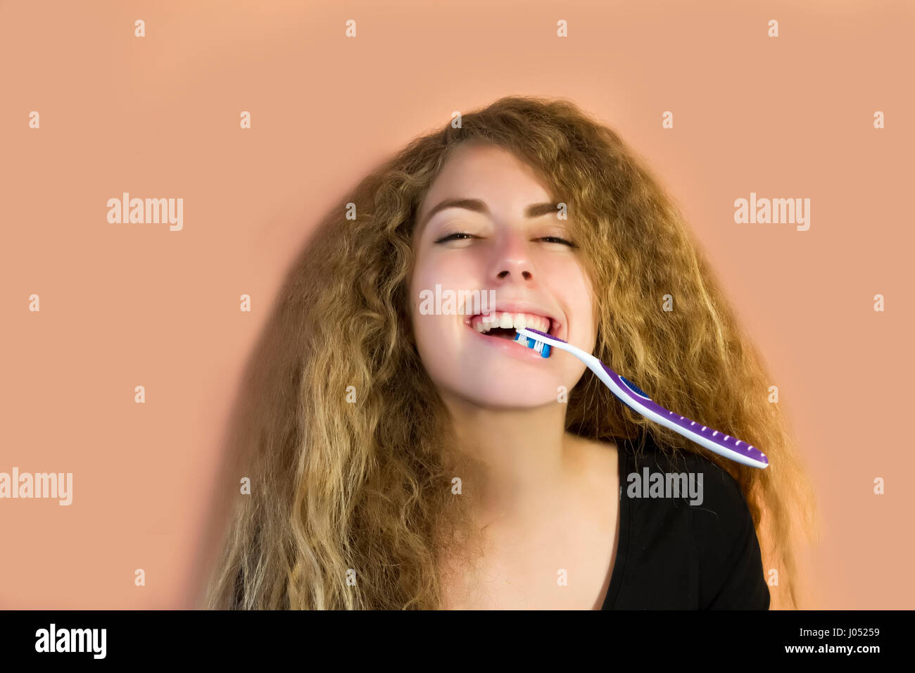 Portrait of beautiful young woman brushing teeth. Pink background Stock ...