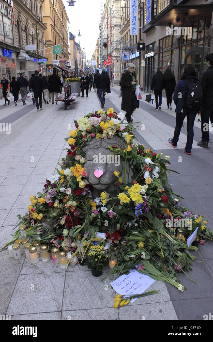 A concrete barricade depicting a lion animal, covered with flowers and ...