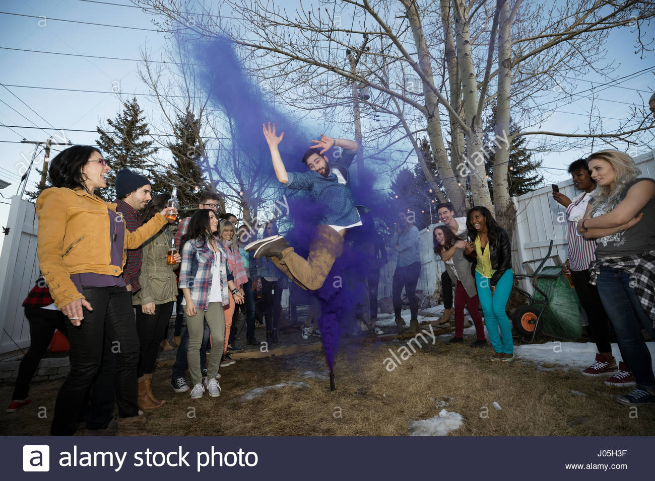 Young man jumping in blue smoke powder at party Stock Photo - Alamy