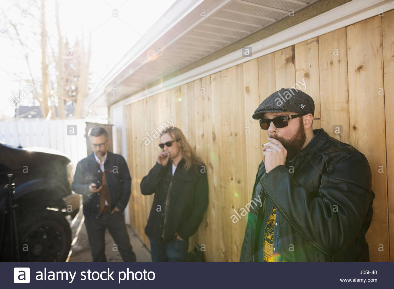 Cool music band musicians smoking cigarettes along sunny wall Stock ...