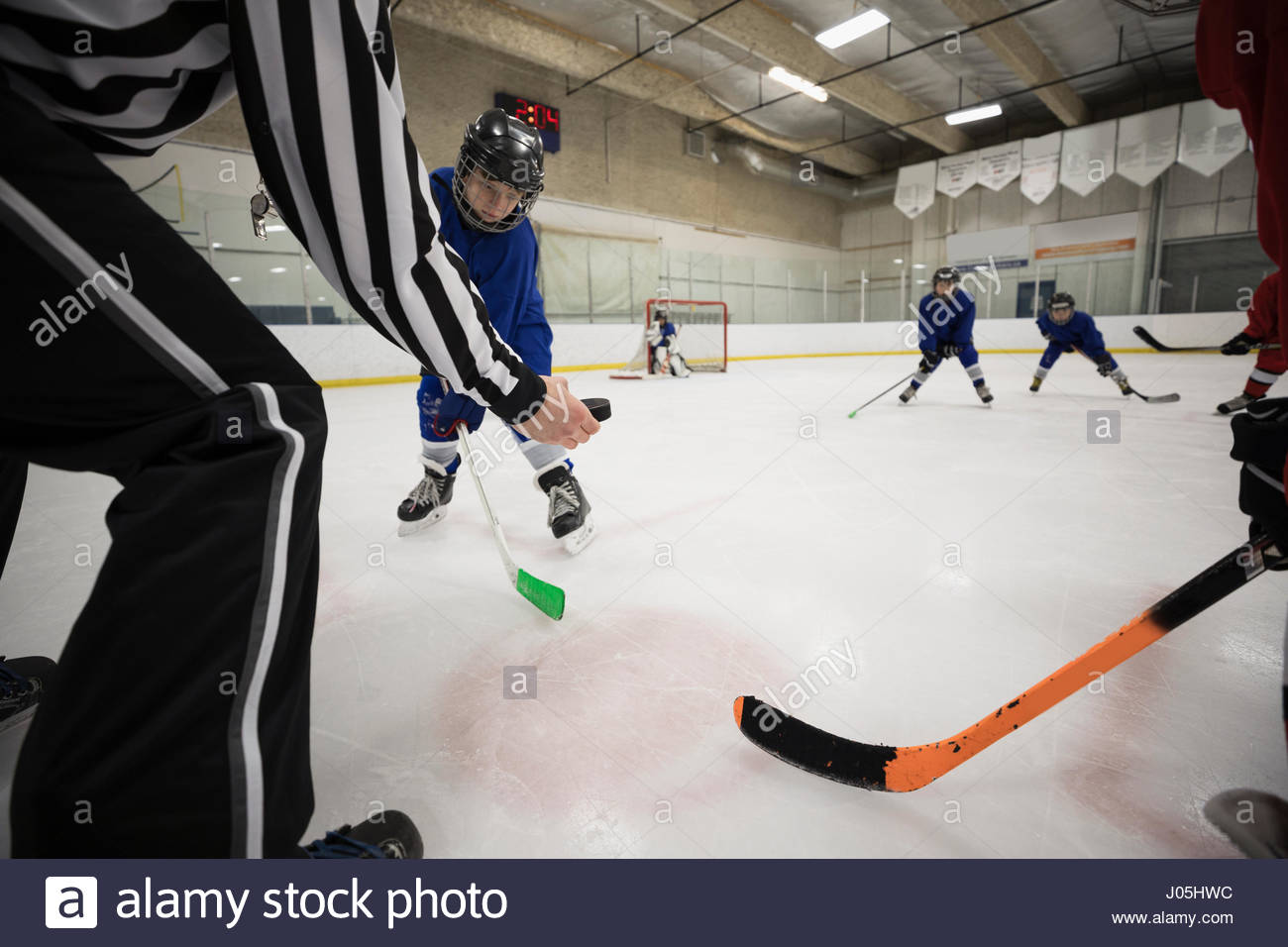 Referee dropping puck for boy ice hockey players ready for face off ...