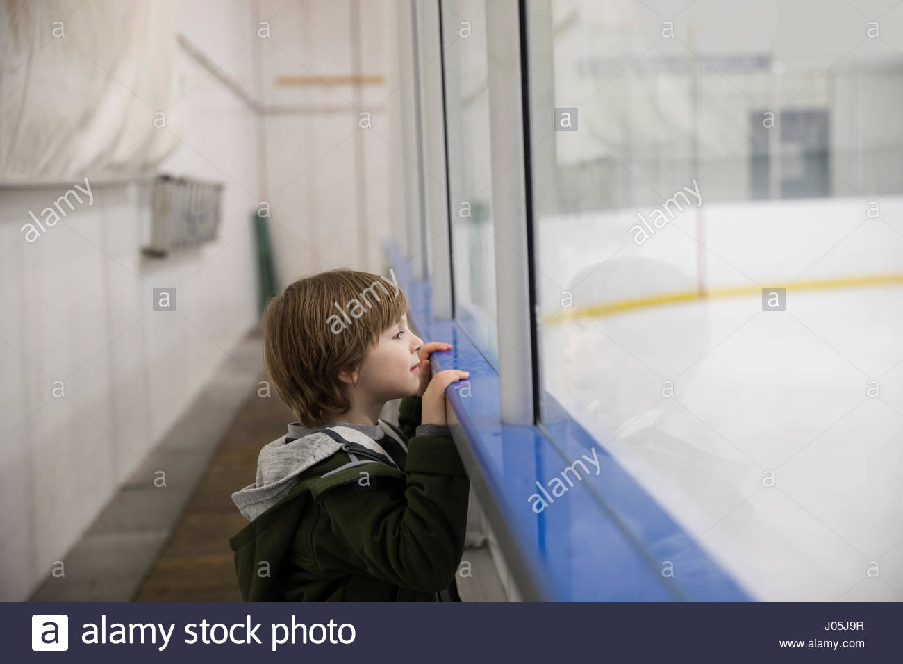Curious boy standing at railing watching ice hockey rink Stock Photo ...