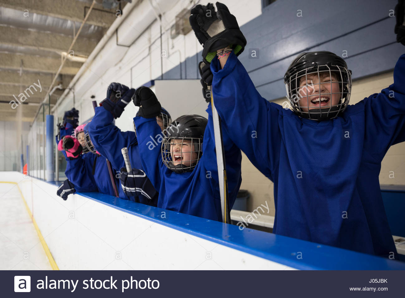 Boy ice hockey players cheering from bench Stock Photo - Alamy