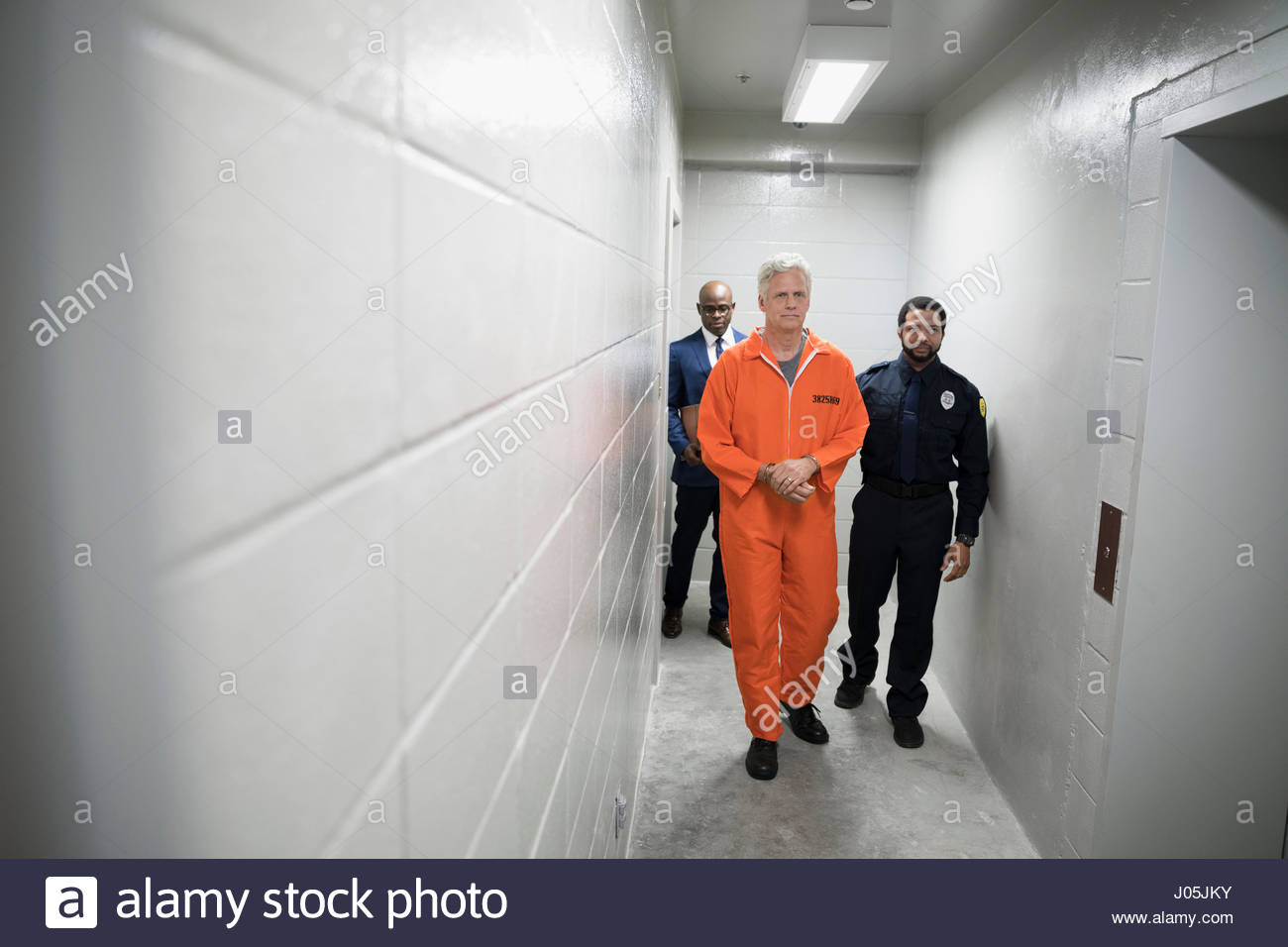 Bailiff walking prisoner in orange jumpsuit down corridor in jail Stock ...