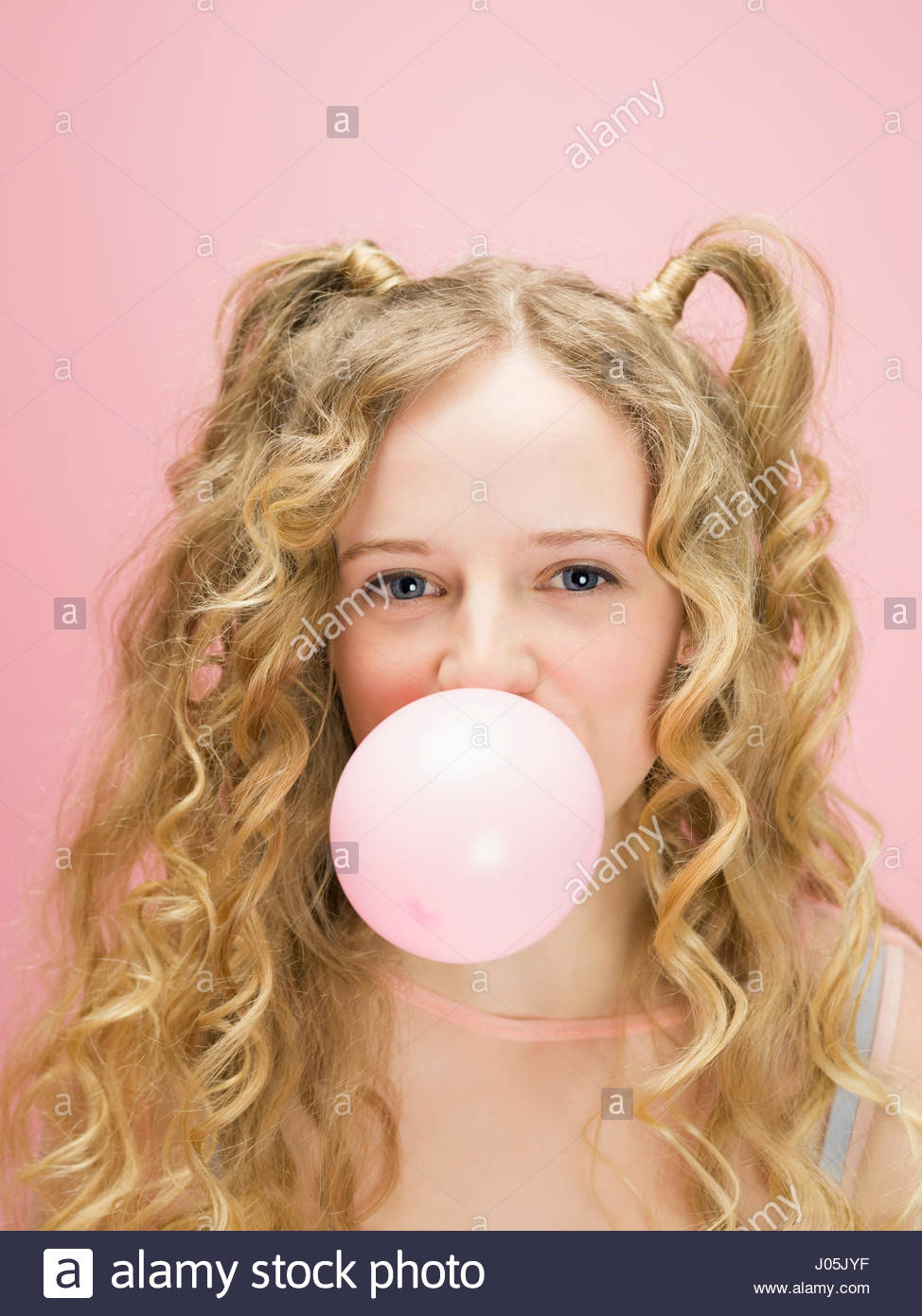Portrait Young Woman With Long Curly Blonde Hair Blowing Bubble Gum