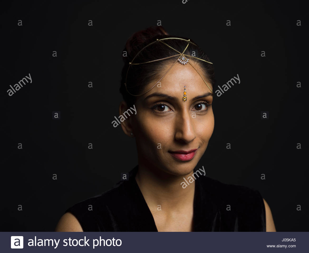 Portrait confident Indian woman with bindi against black background ...