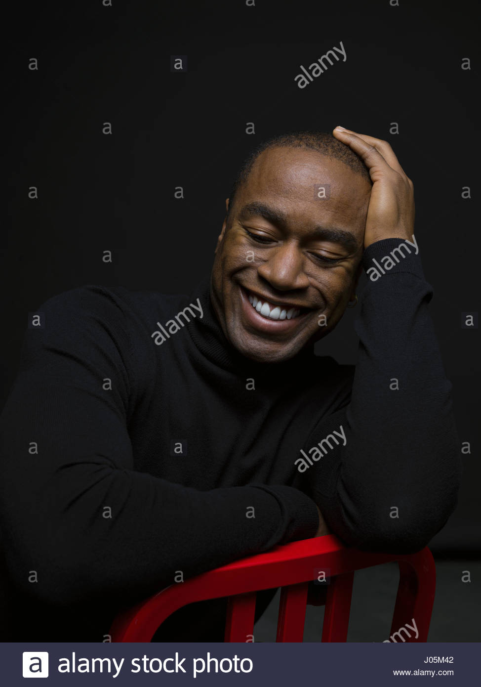 Portrait smiling African American man looking down with head in hand ...