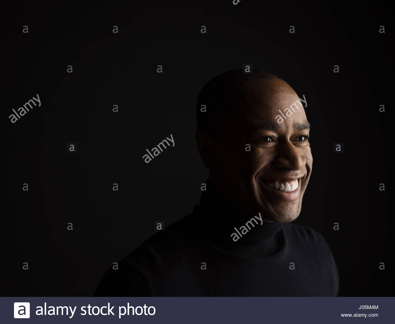 Portrait smiling African American man looking away against black ...
