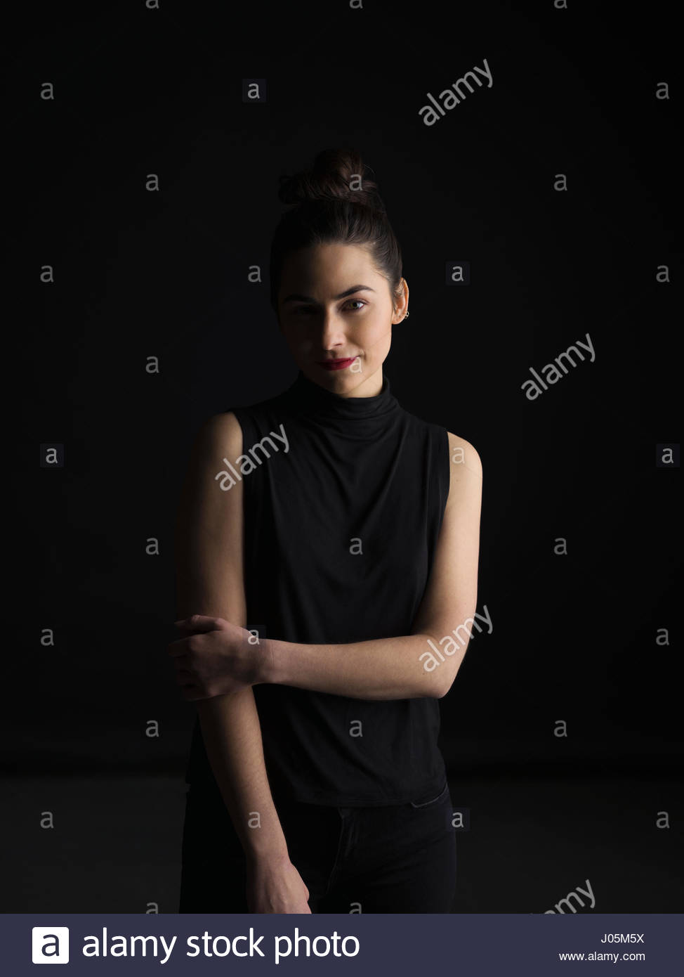 Portrait confident brunette woman in shadow against black background ...