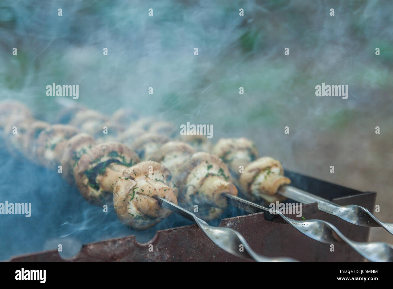 Grilled mushrooms on skewers cooked in a brazier, close-up, retro ...