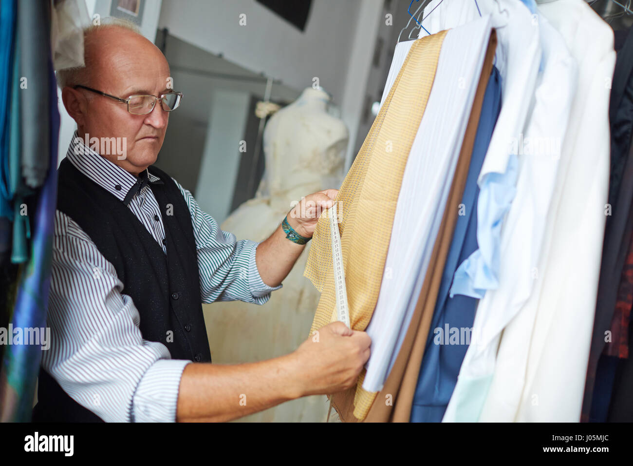 Professional tailor measuring length of fabric Stock Photo - Alamy