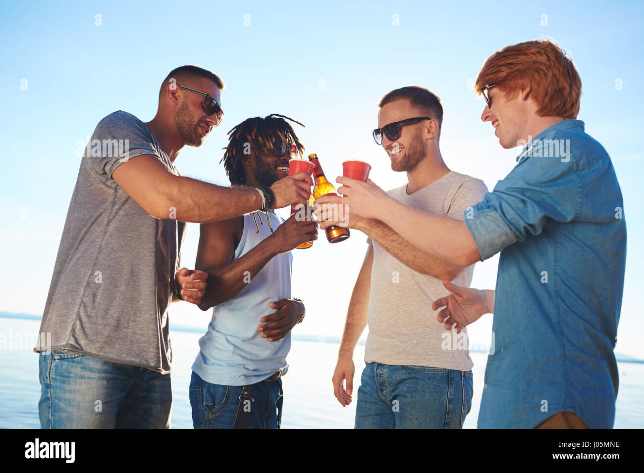 Happy guys toasting with drinks on the beach Stock Photo - Alamy