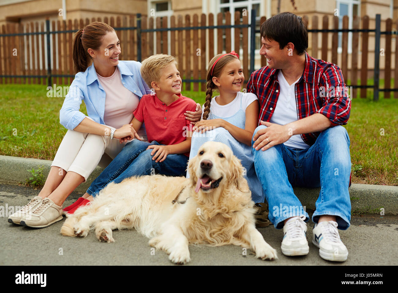 Affectionate family having rest on lawn by their house Stock Photo - Alamy