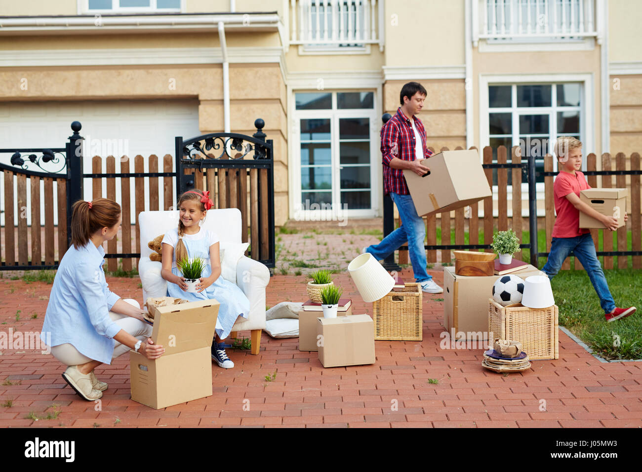 Little girl talking to her mother while packing boxes, man and boy ...