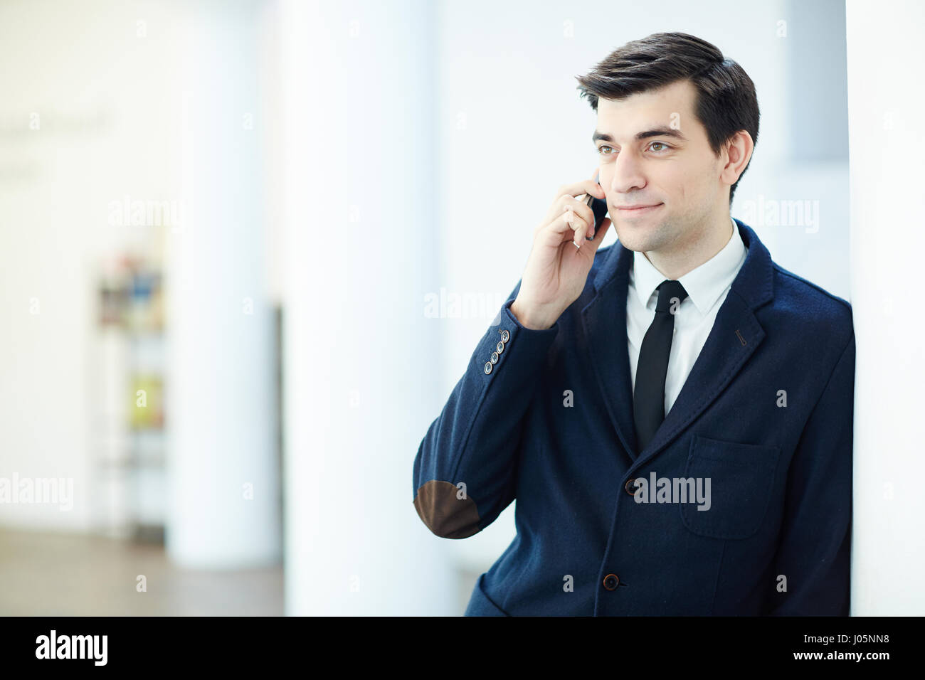 Confident young man in suit speaking on mobile phone Stock Photo - Alamy