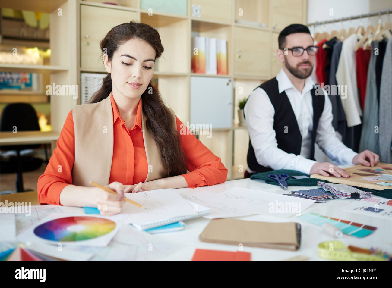Young woman working as fashion designer with her assistant on ...