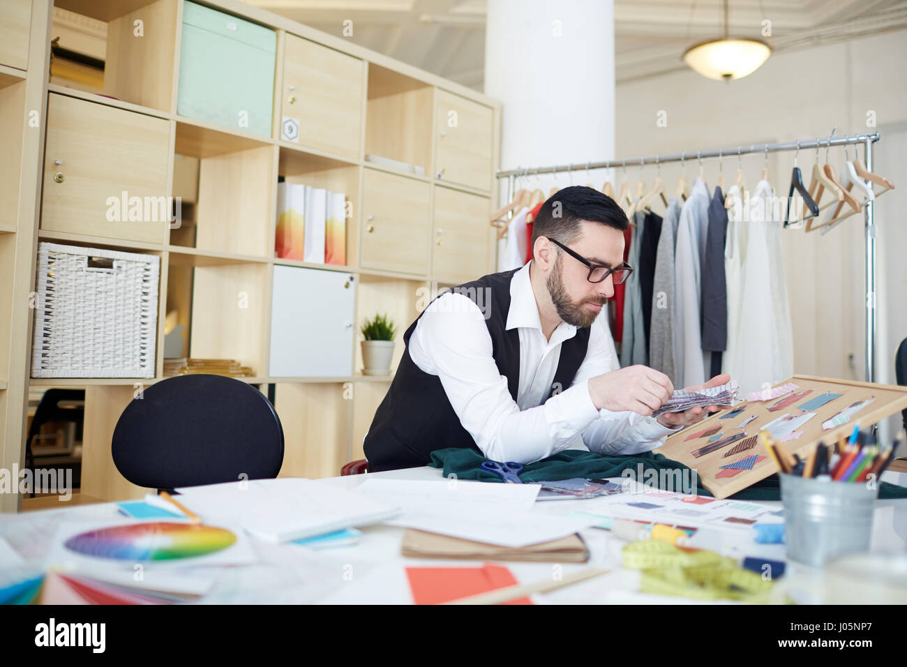 Modern tailor choosing fabric samples for new clothes collection Stock ...
