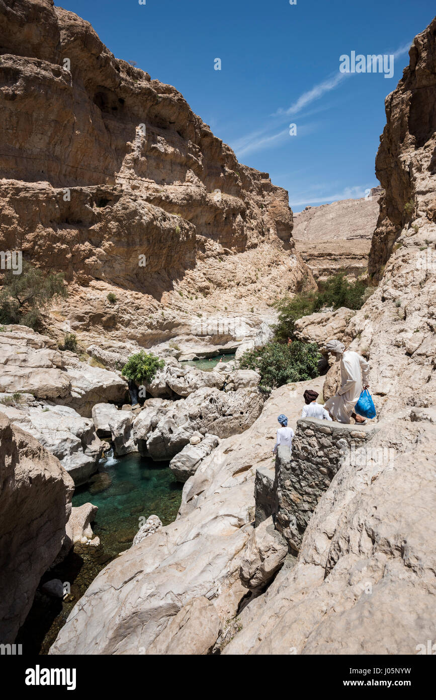 Omanese people walk towards the pools while tourists swim in the clear ...