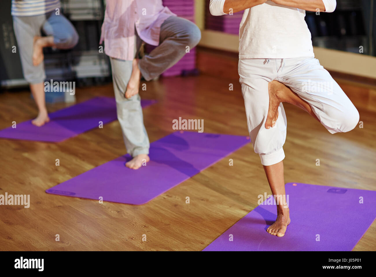 Three humans standing on one leg during yoga exercise Stock Photo - Alamy