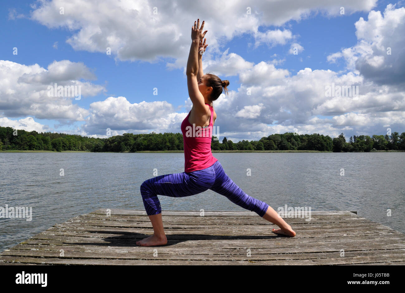Young active woman doing yoga positions on the wooden pier at the ...