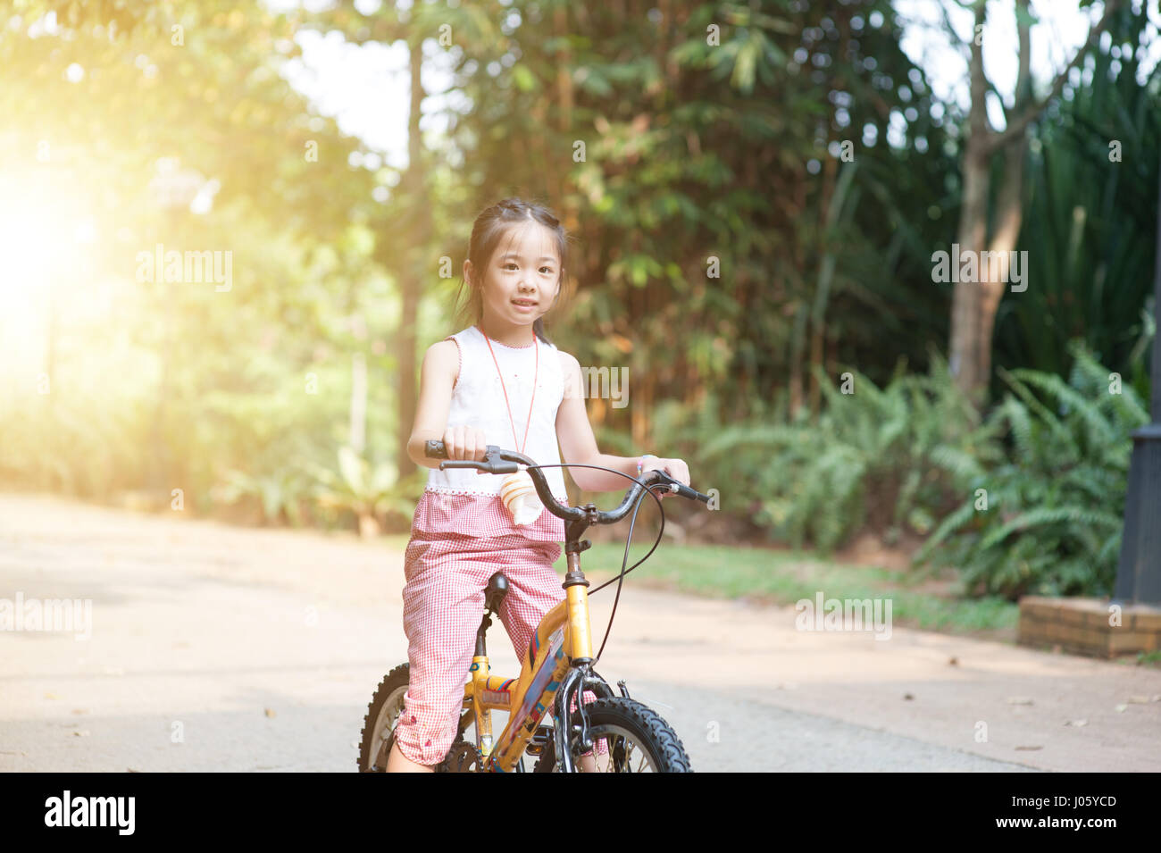 Portrait of active Asian child riding bicycle outdoors. Kid having fun ...