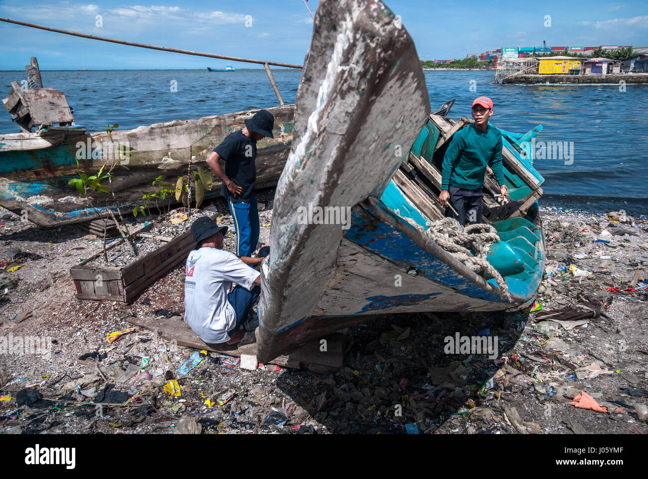 Fishermen repairing a boat on a landfill beach in the coastal village ...
