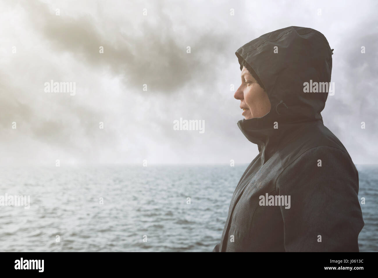 Optimistic female person enjoying morning sunlight at sea coastline on ...