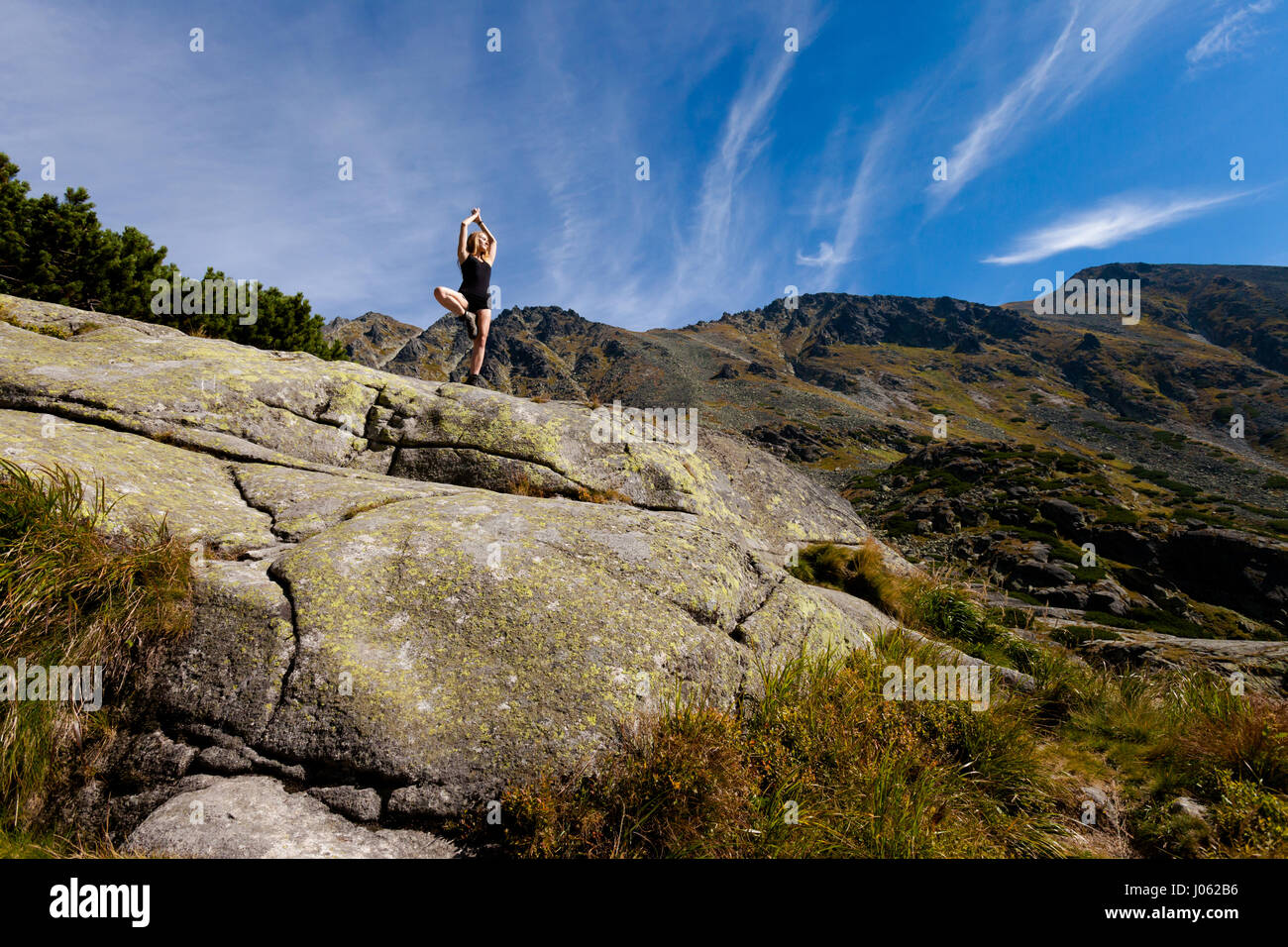Yoga exercising in Tatry mountains Vriksha-asana - tree pose. Tourist ...