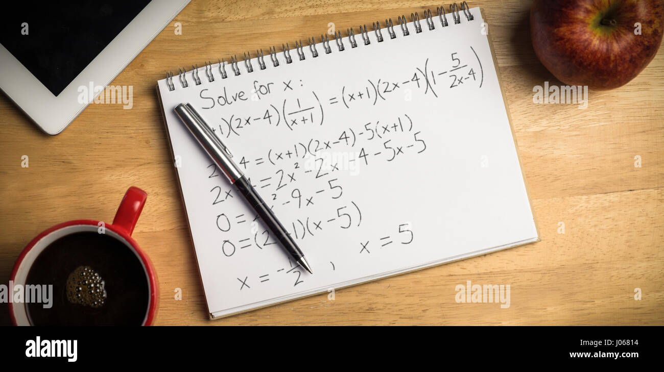 Equations over black background against overhead of notepad and pen ...