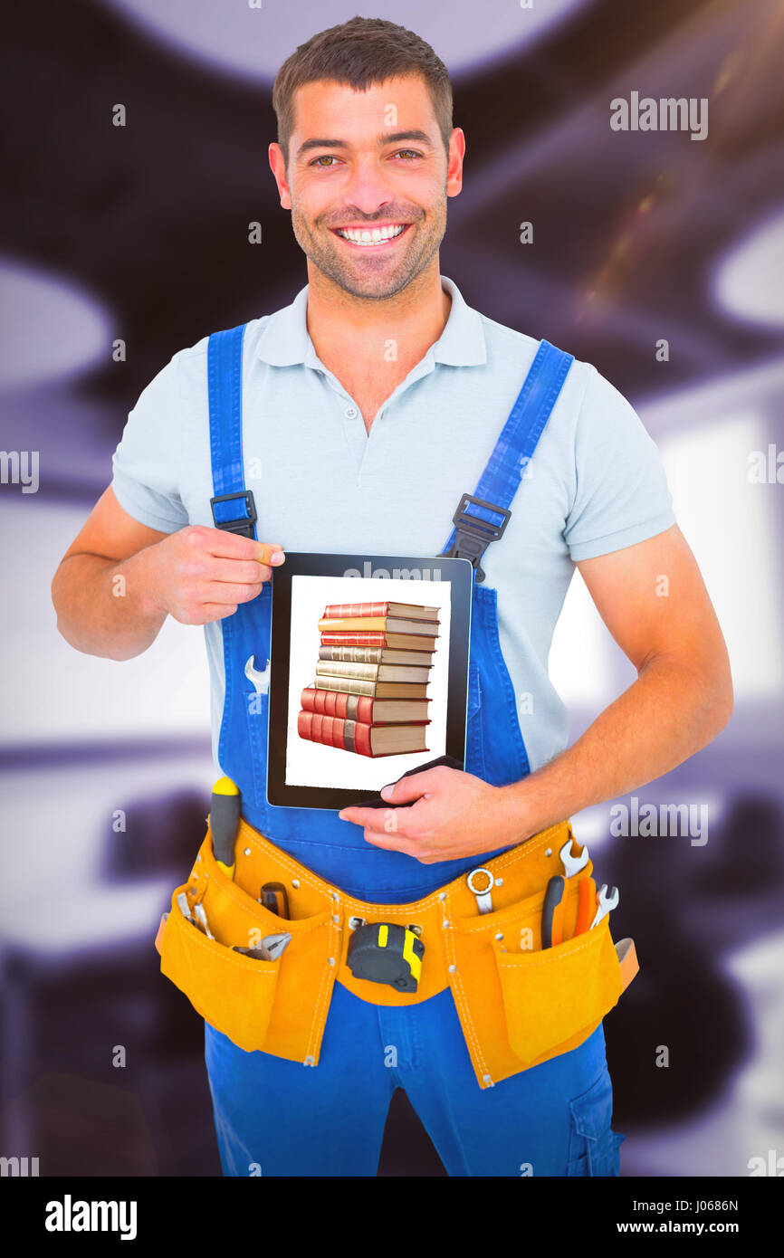 Happy repairman in overalls holding digital tablet against classroom ...