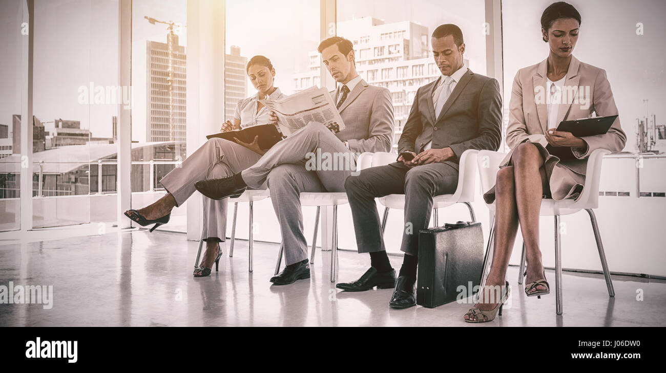Well dressed business people sitting together in waiting room at office ...