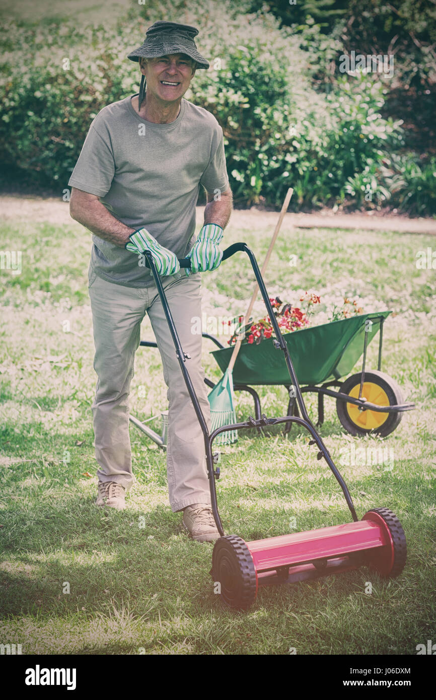 Full length portrait of a smiling man mowing the lawn Stock Photo - Alamy