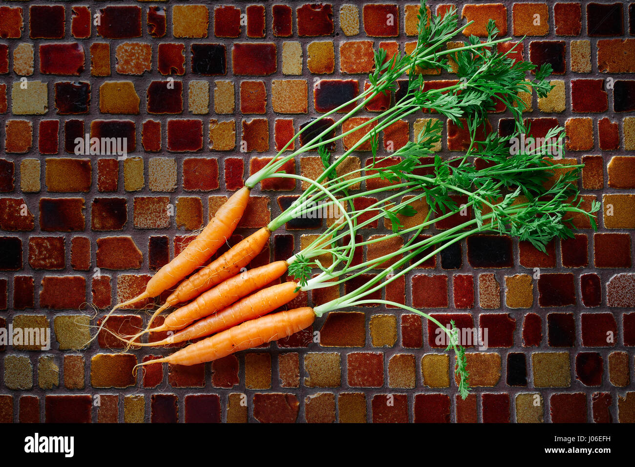 Mini Carrot vegetables on a tiles table background Stock Photo - Alamy