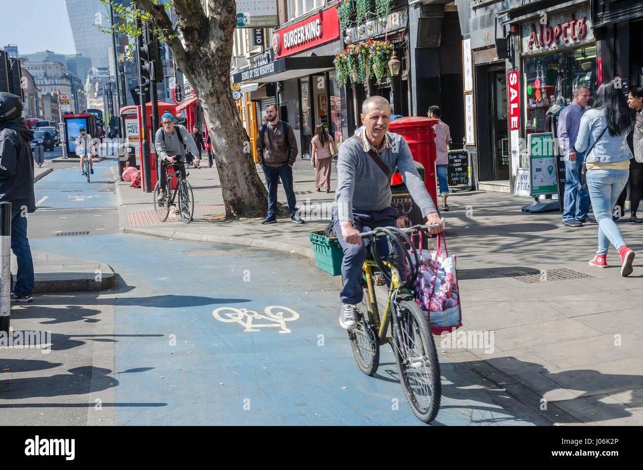 A man on a bicycle cycles down a cycle lane at the side of Whitechapel ...