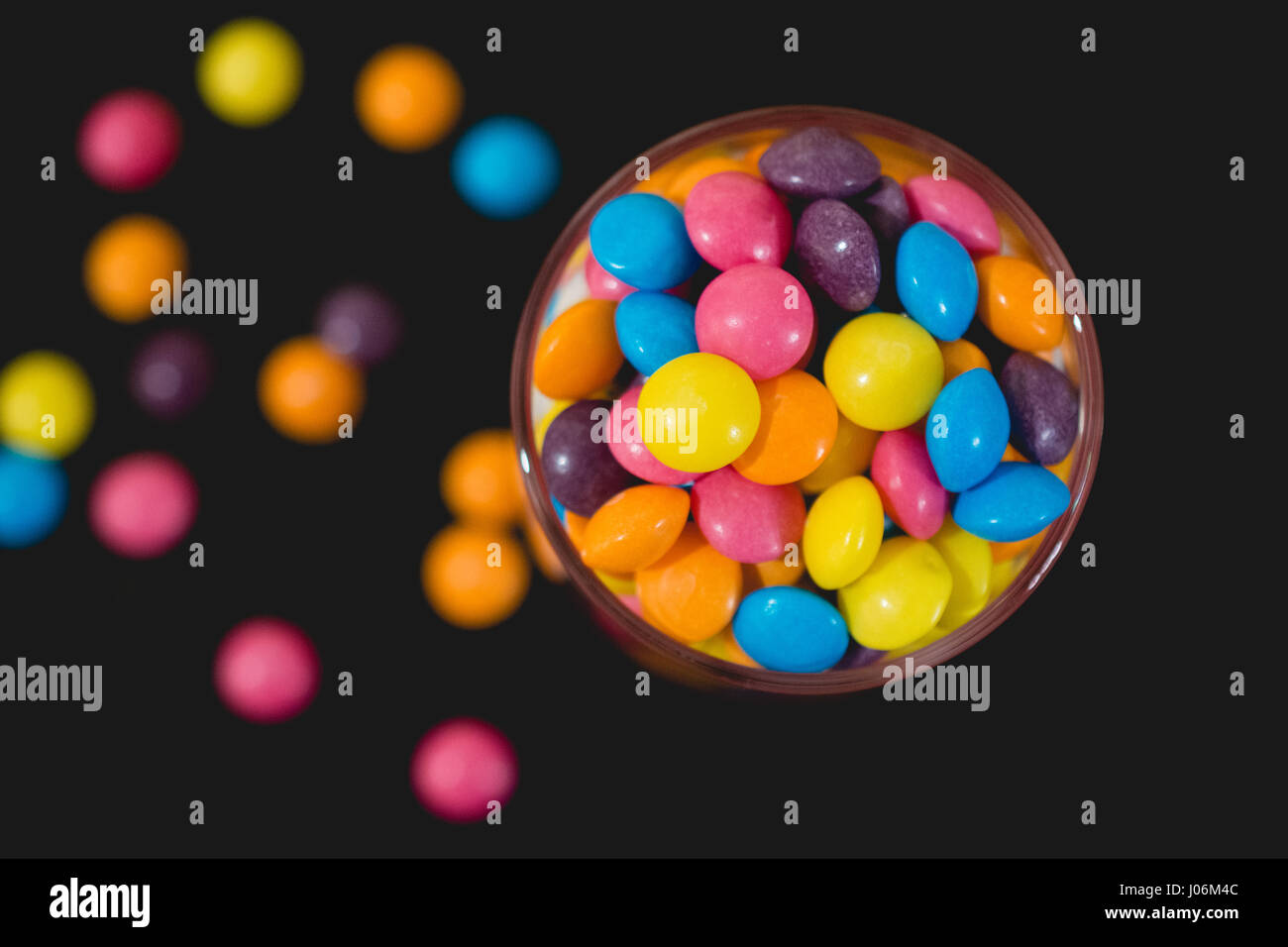 smarties in jar spilling our, on black background Stock Photo - Alamy