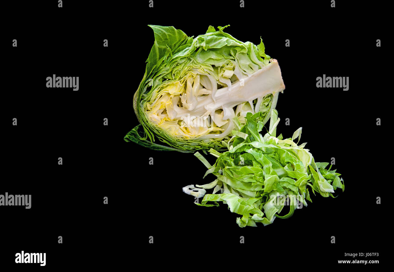 green cabbage half head half chopped strips for salad on black ...