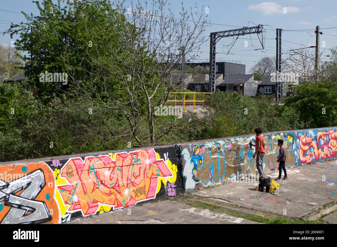 Father and son spraying a wall with graffiti in a playground in ...