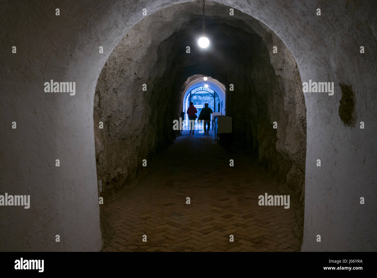 People walking through illuminated tunnel, Aragonese Castle, Ischia ...