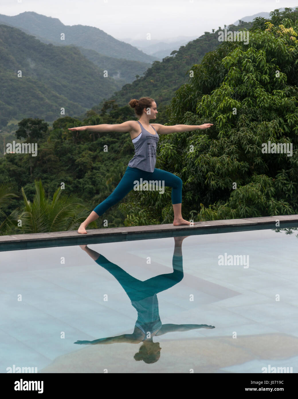 Teenage girl stretching at poolside in resort near mountains, Yelapa ...