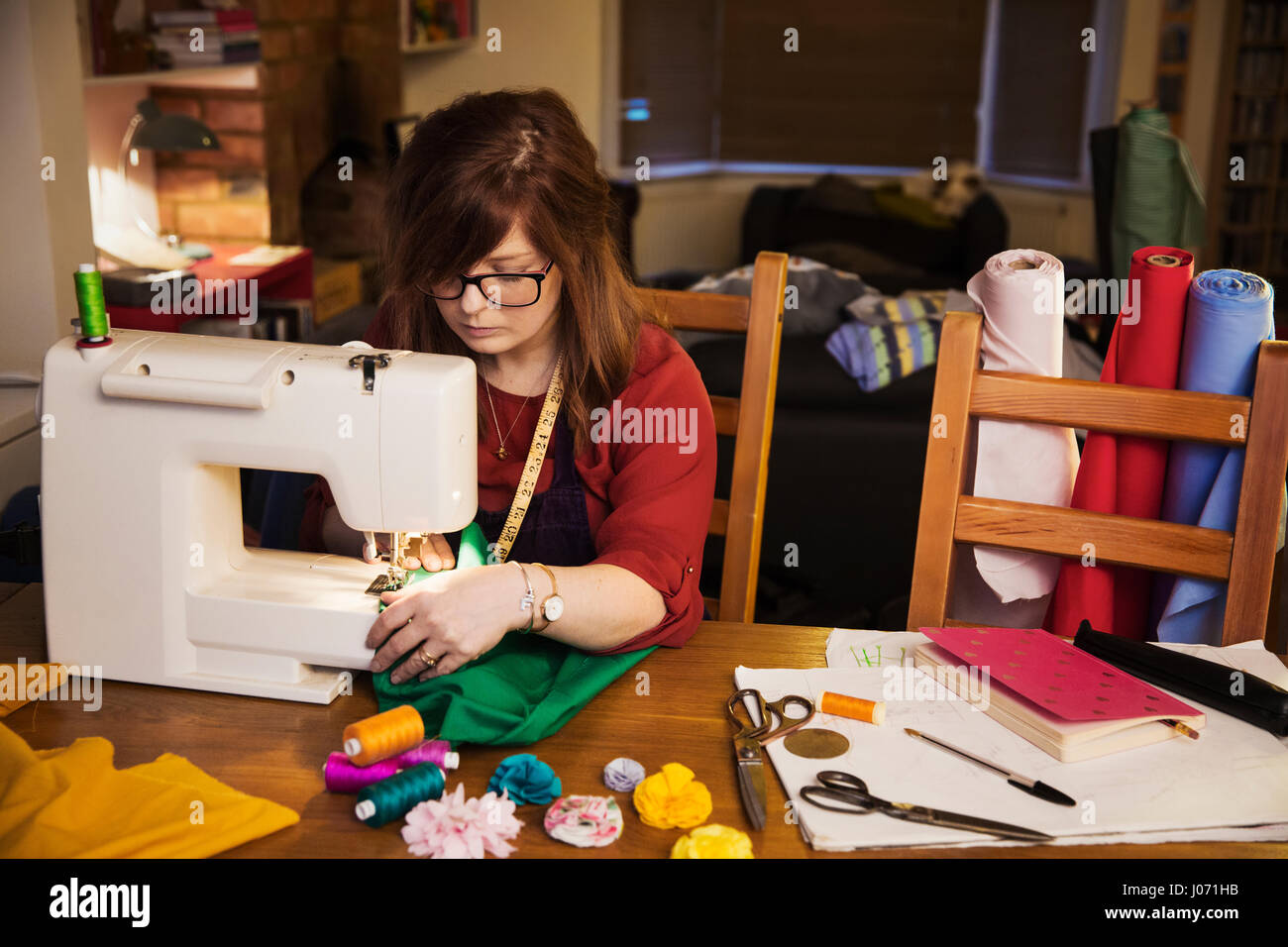 A woman using an electric sewing machine on a table, surrounded by ...