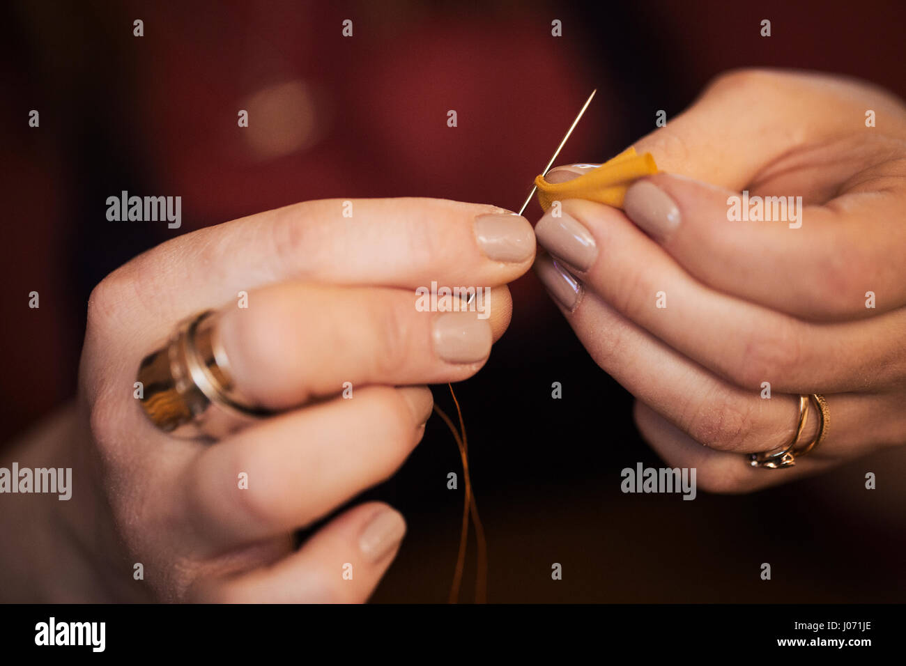 A woman using a needle threaded with cotton thread Stock Photo - Alamy