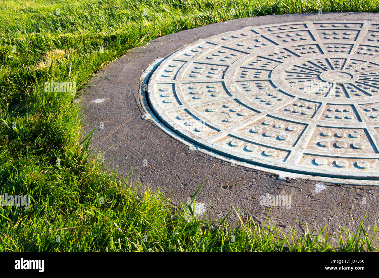 Metal manhole in a background of green grass on the field Stock Photo ...