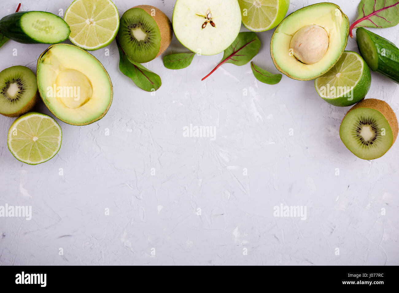 Frame of green vegetables and fruits over light gray plaster table ...