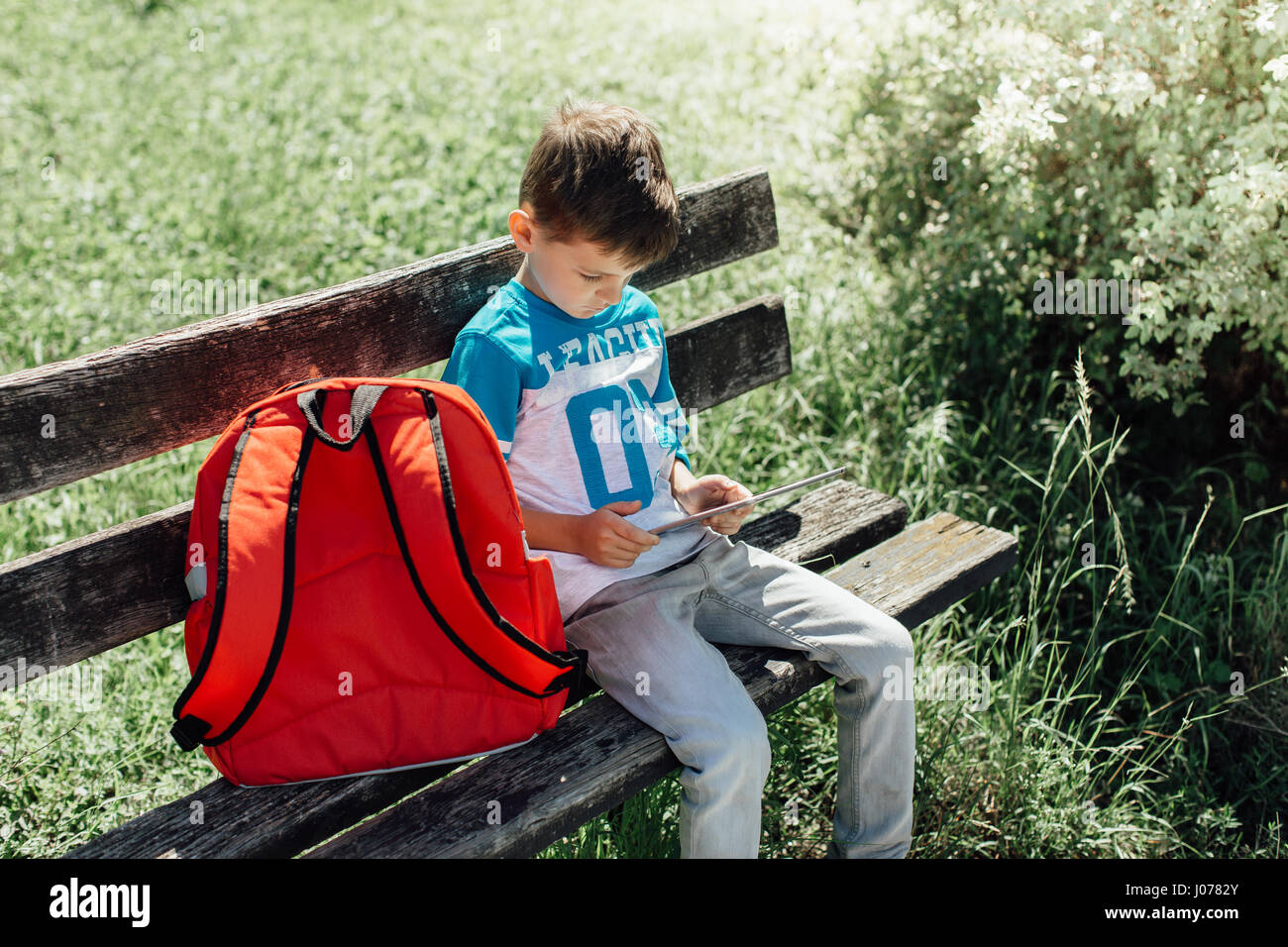 Schoolboy taking a break playing with a tablet on a bench Stock Photo ...