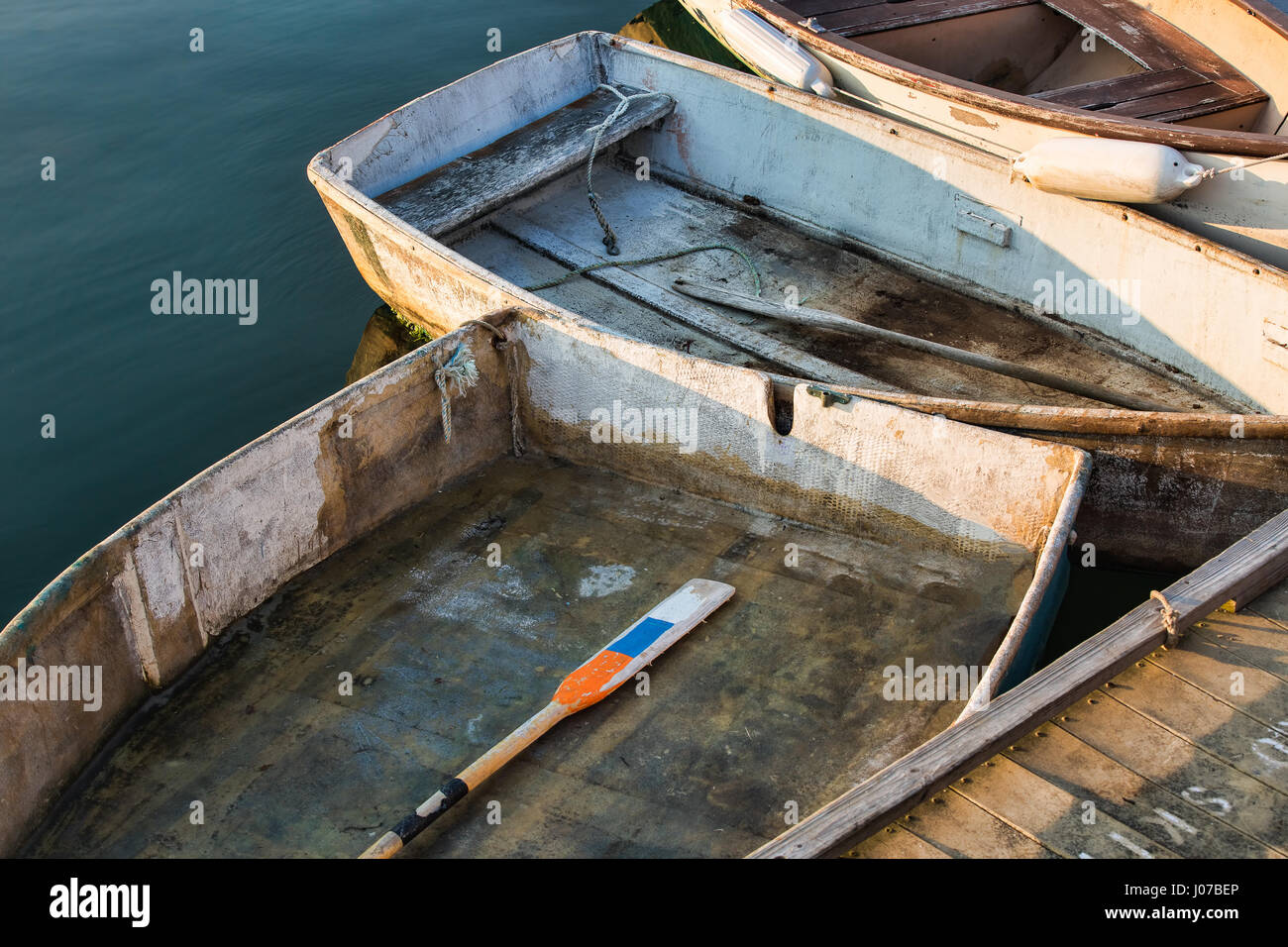 A close up shot a three rustic old wooden row boats tied to a pier ...