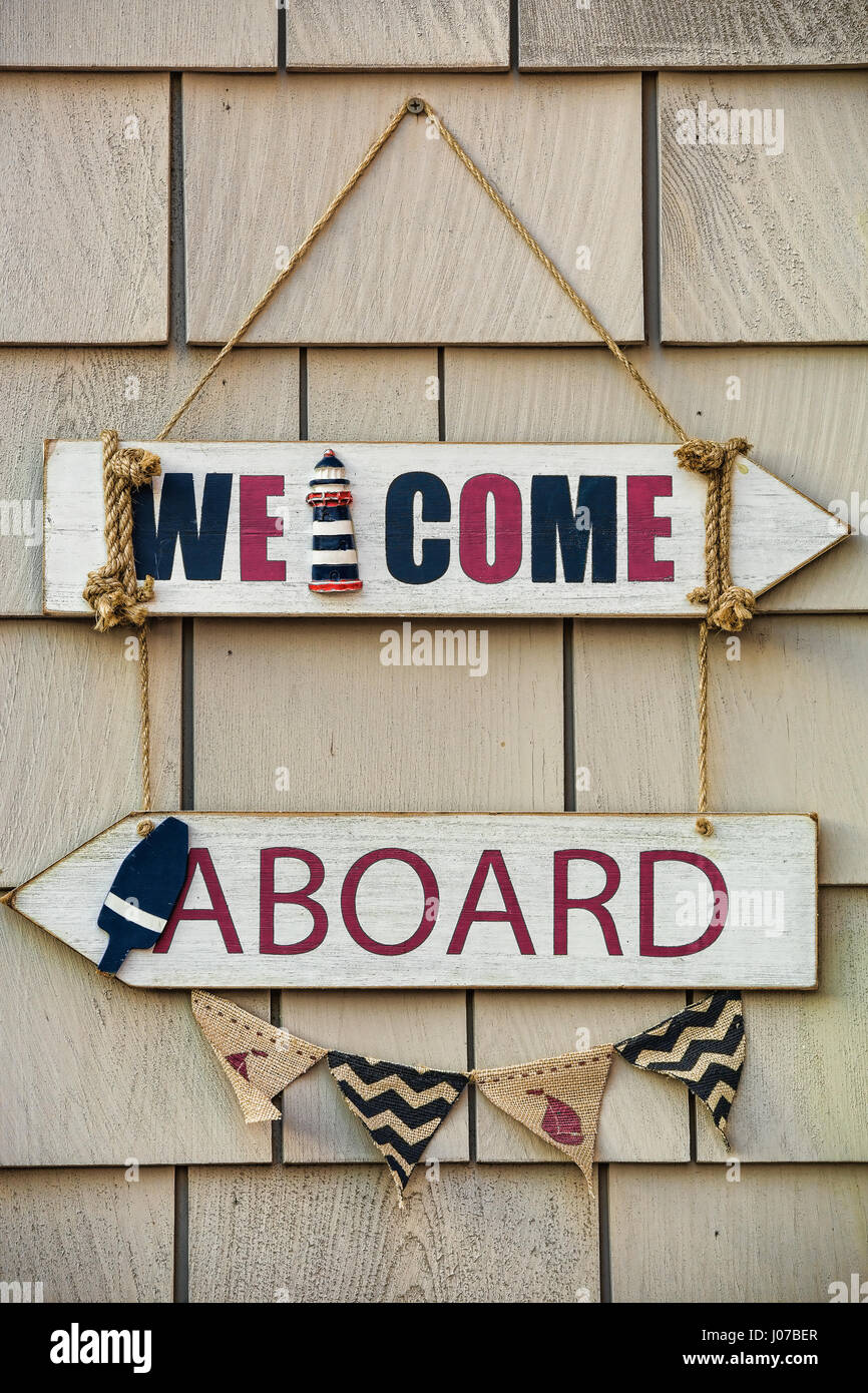 Hand painted wooden welcome aboard sign hanging on a rustic shingled ...